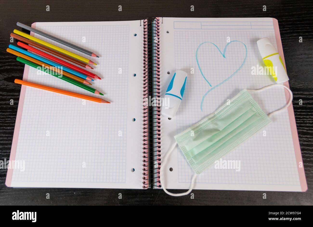 Overhead shot of colored pencils and protective mask on an open ...