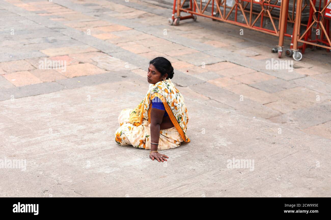 Indian woman sitting in front of an temple, people sitting near the ...