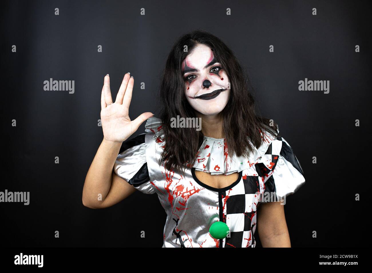 woman in a halloween clown costume over isolated black background doing ...