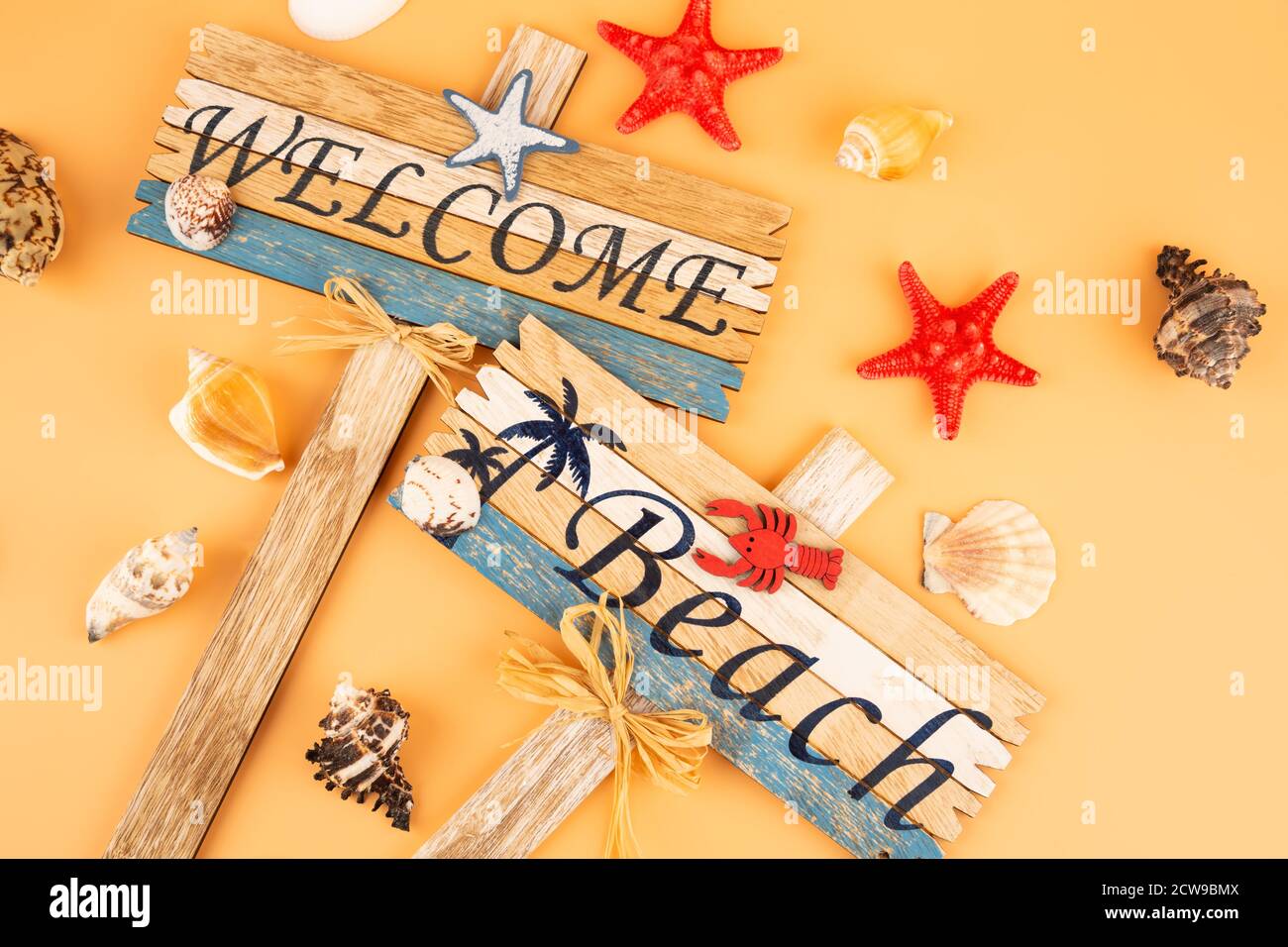 Wooden signs welcome beach, starfish and shells on yellow background ...