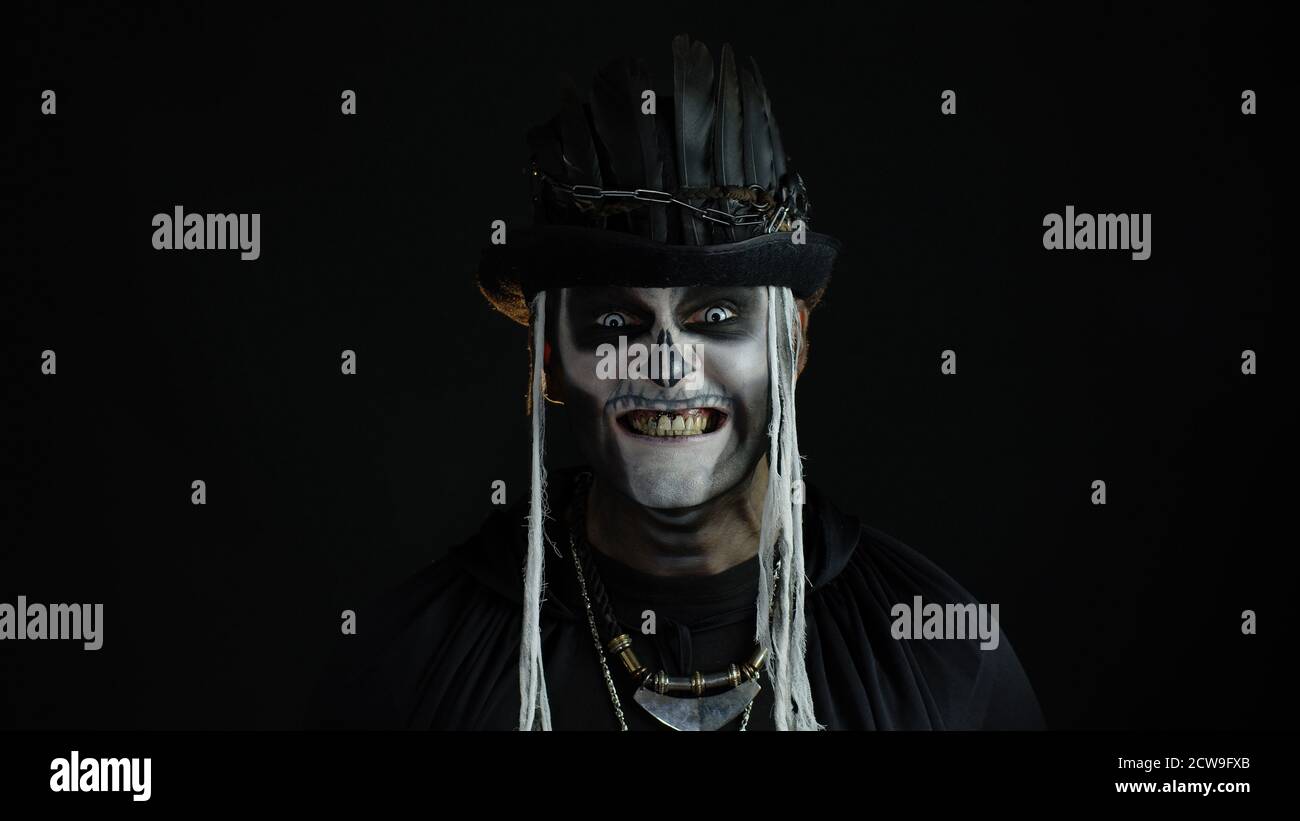 Creepy man with skeleton makeup in top-hat with feathers. Guy making ...