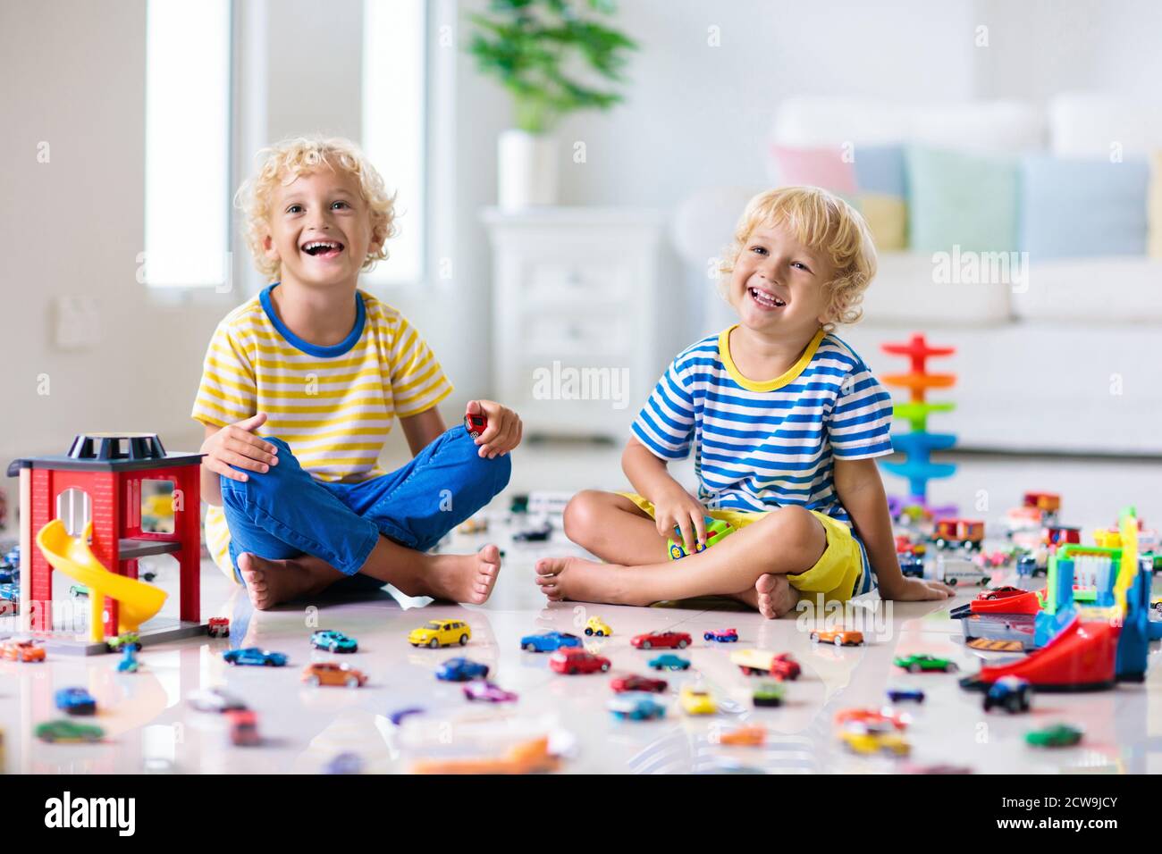 Kids play with toy cars in white room. Little boy playing with car and ...