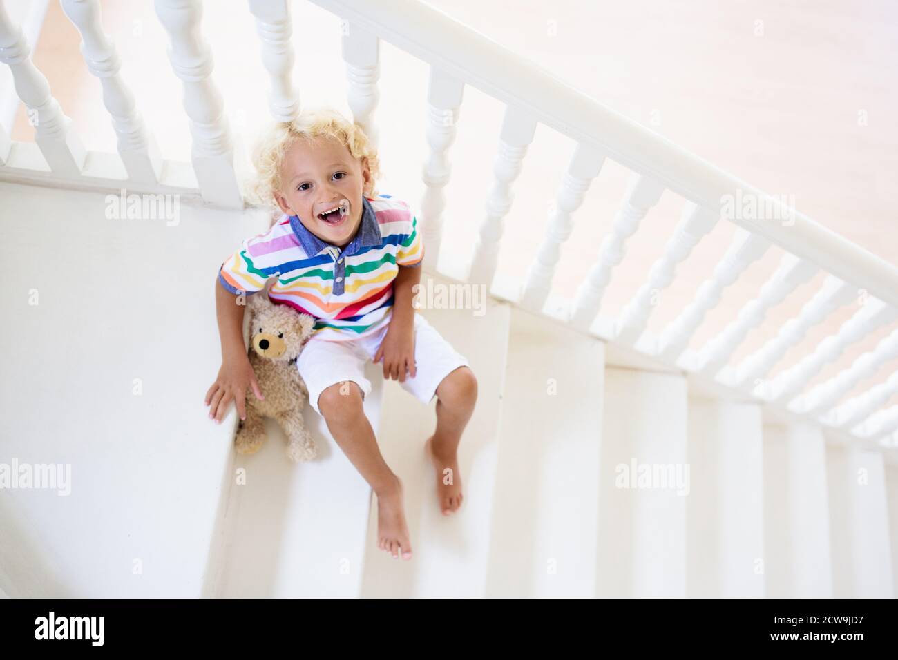 Kid walking stairs in white house. Little boy playing in sunny ...