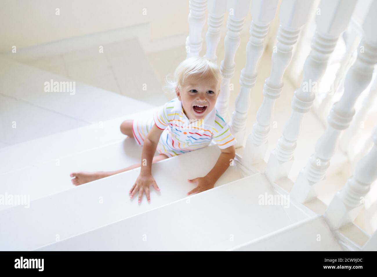 Kid walking stairs in white house. Baby boy playing in sunny staircase ...