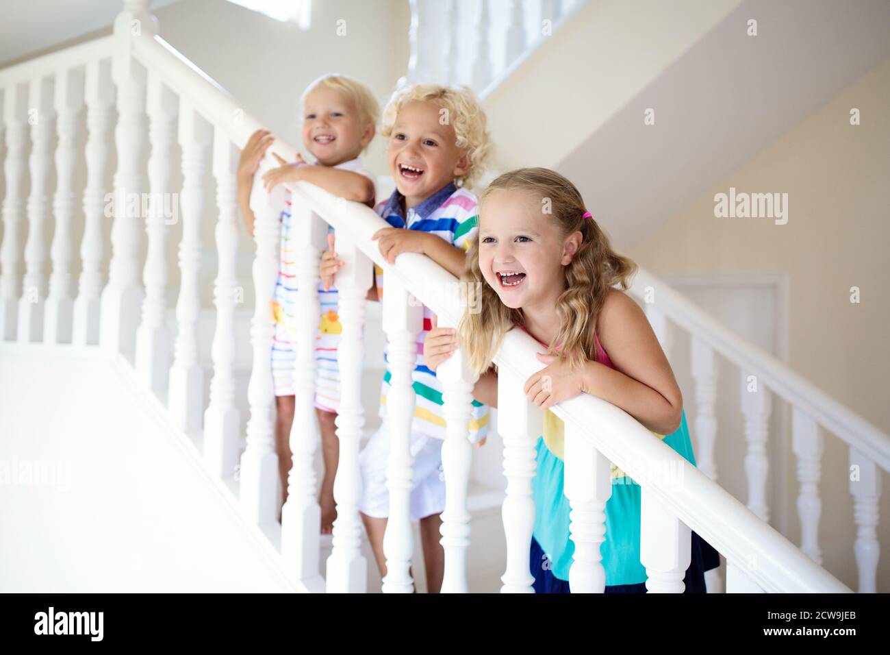 Kids walking stairs in white house. Children playing in sunny staircase ...