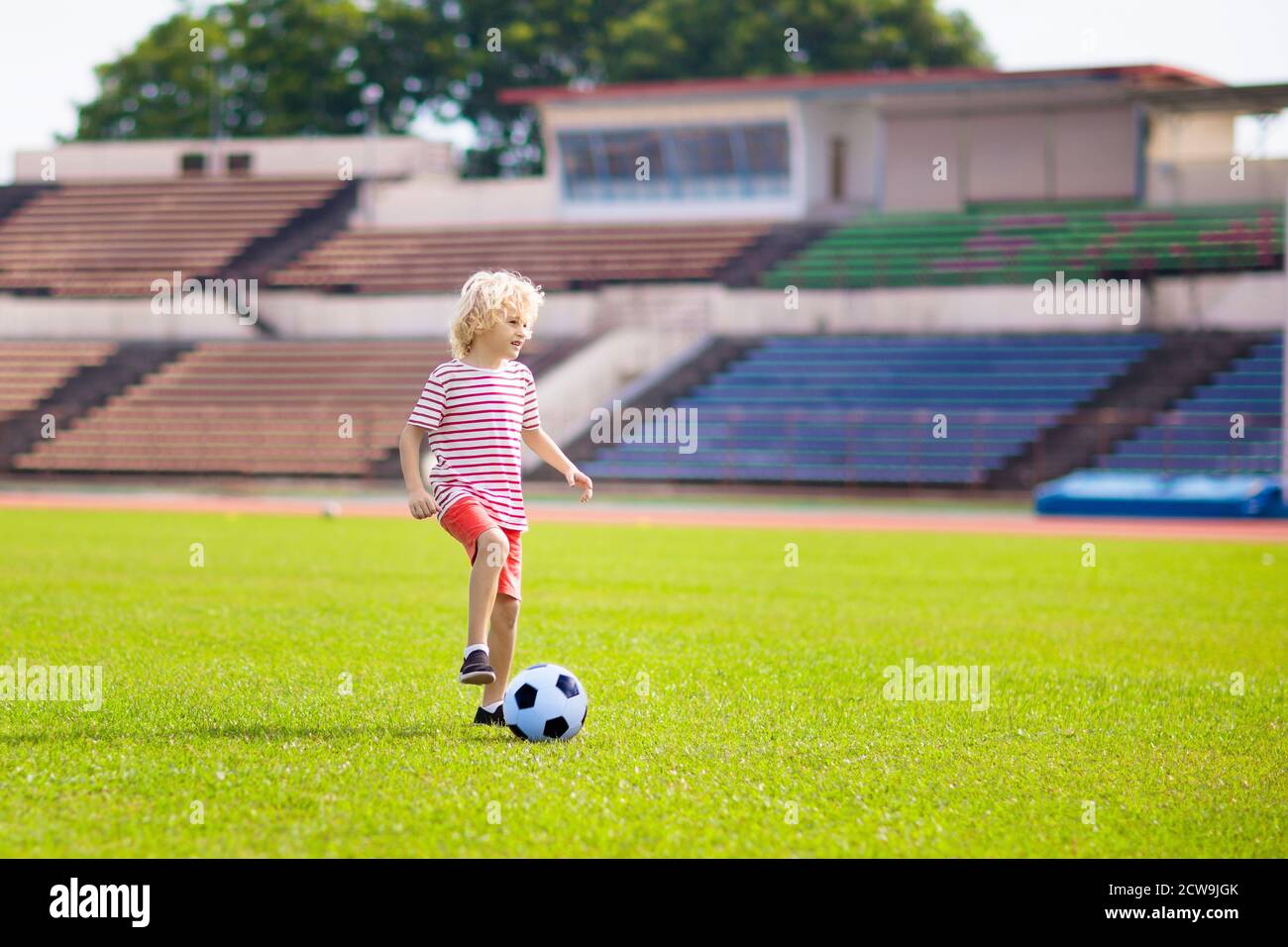 Kids play football on outdoor stadium field. Children score a goal ...