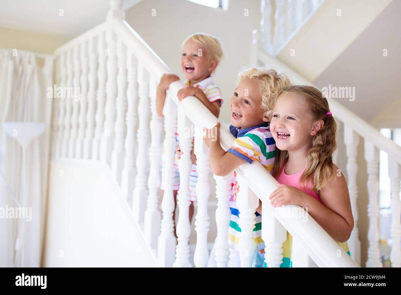 Kids walking stairs in white house. Children playing in sunny staircase ...