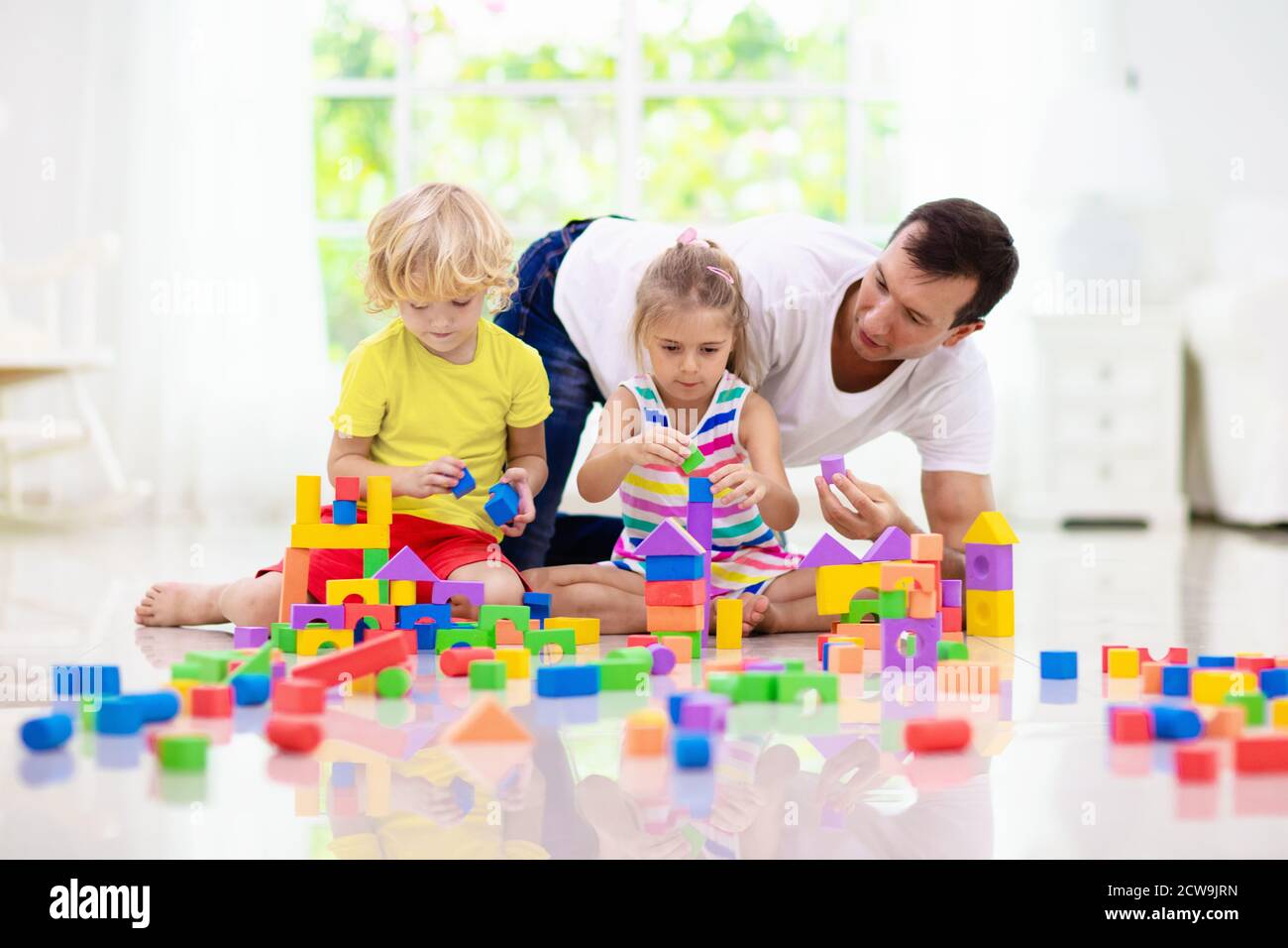 Father and kids play with colorful blocks. Dad, little boy and girl ...