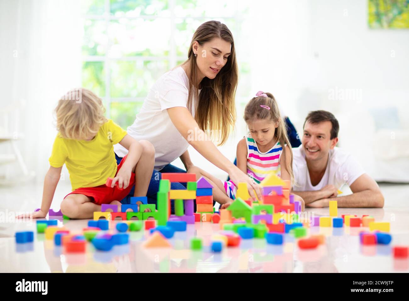 Father, mother and kids play with colorful blocks. Dad, mom, little boy ...