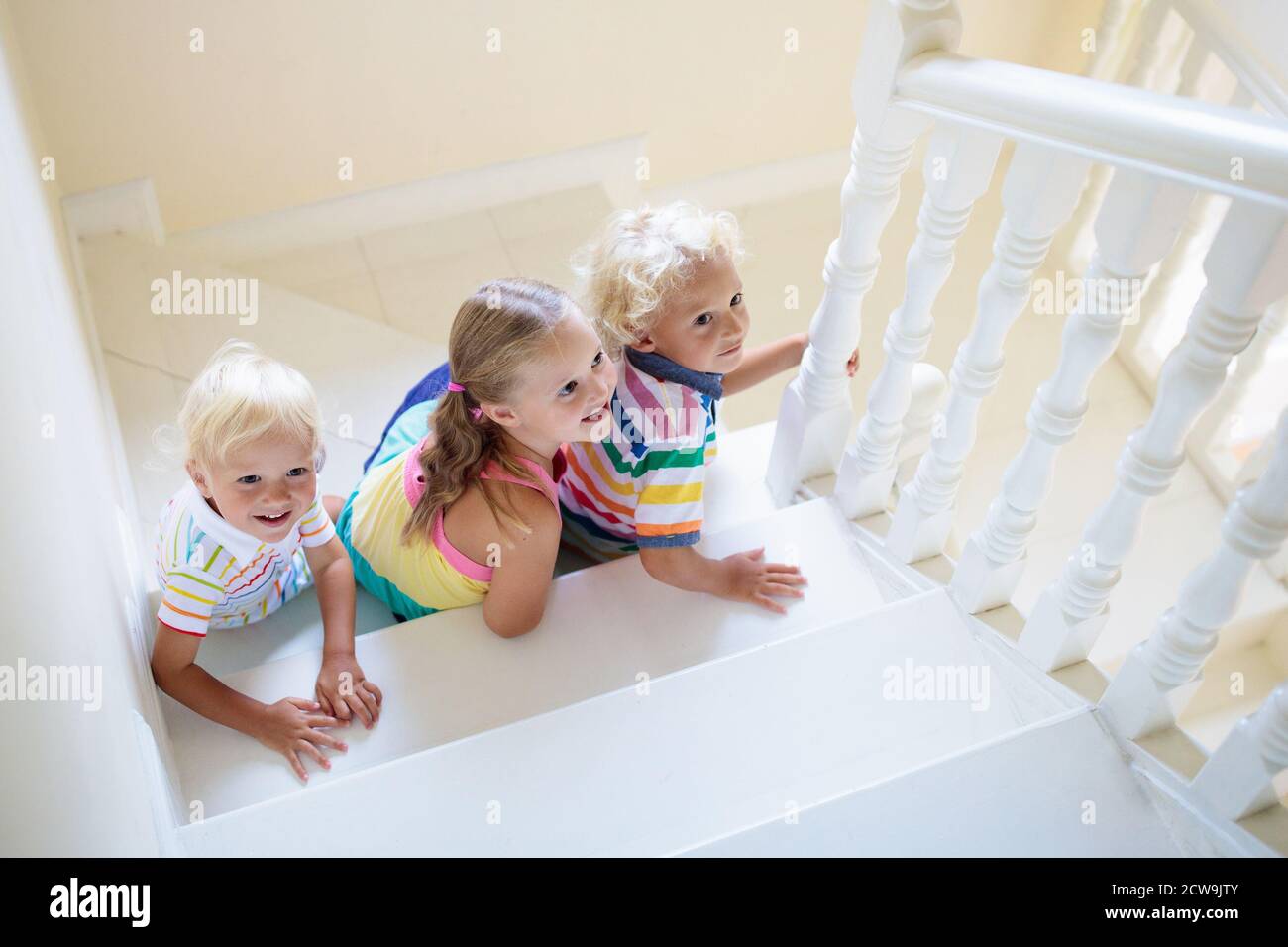 Kids walking stairs in white house. Children playing in sunny staircase ...