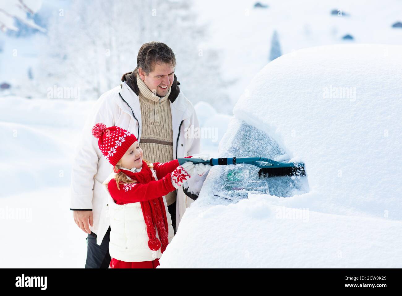 Father and child brushing and shoveling snow off car after storm ...