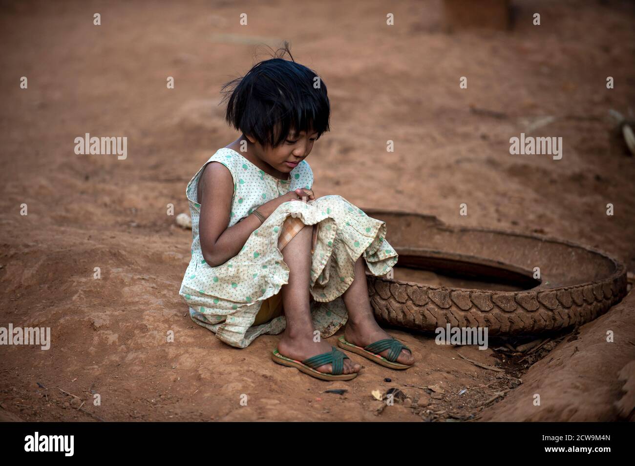 Asian girl A ragged dress sitting on the ground at a rural village ...