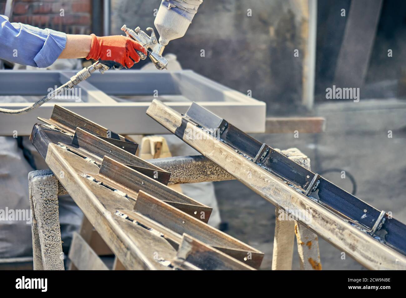 Unrecognizable male worker in protective costume and gloves using spray ...
