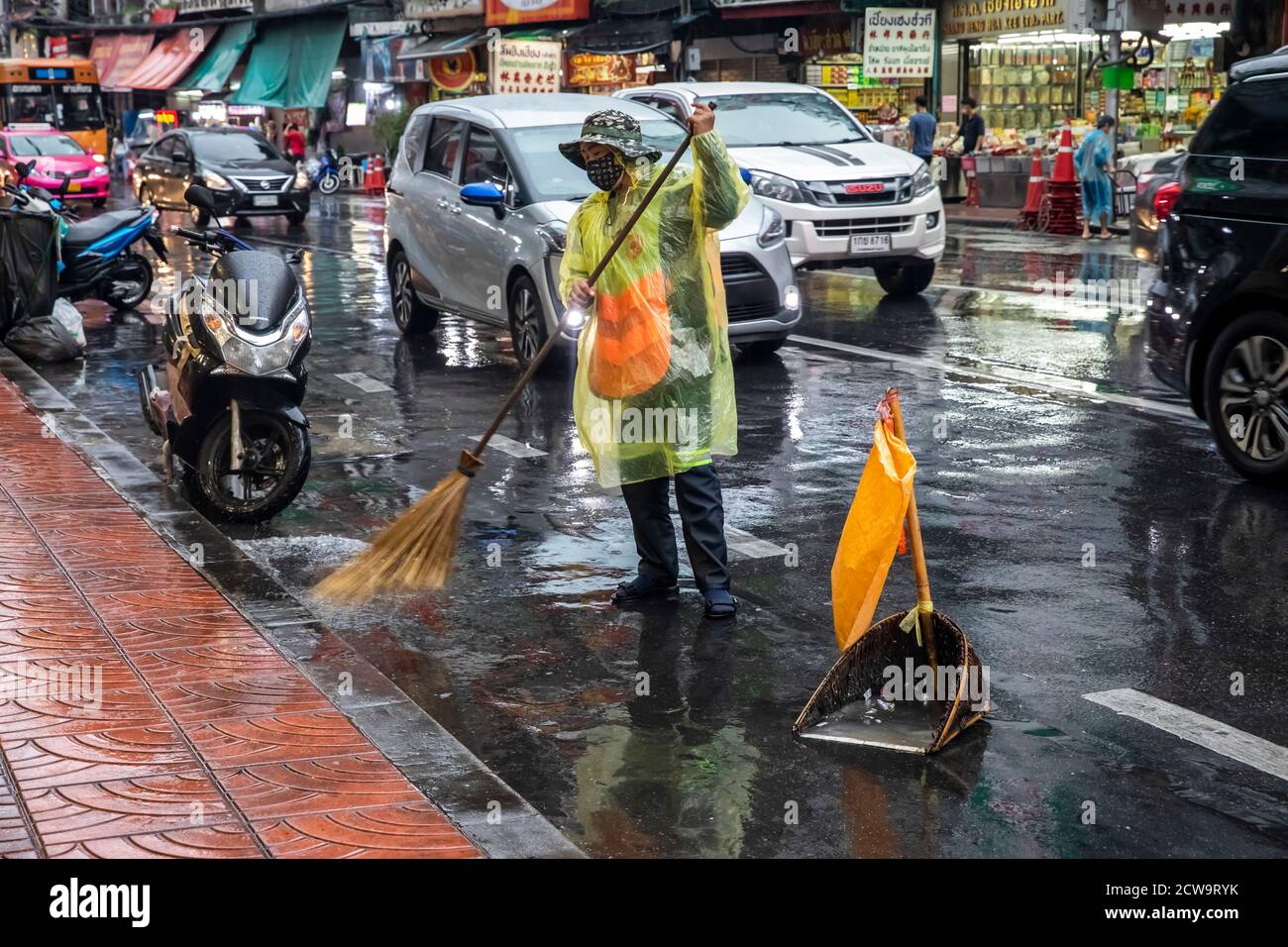 A street sweeper turns his broom and muscle on sweeping rain water ...
