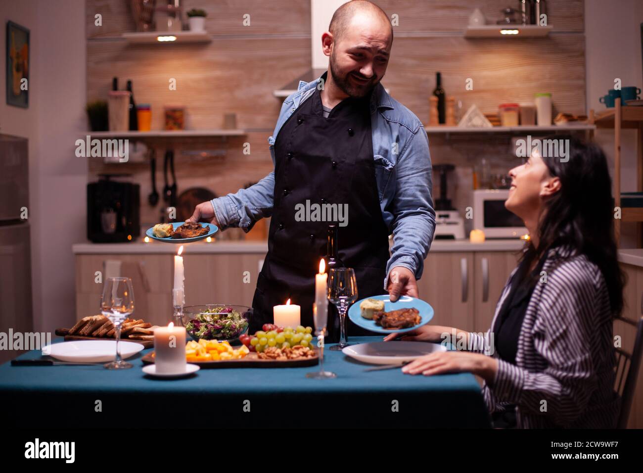 Husband serving wife with tasty food during celebration of relationship ...