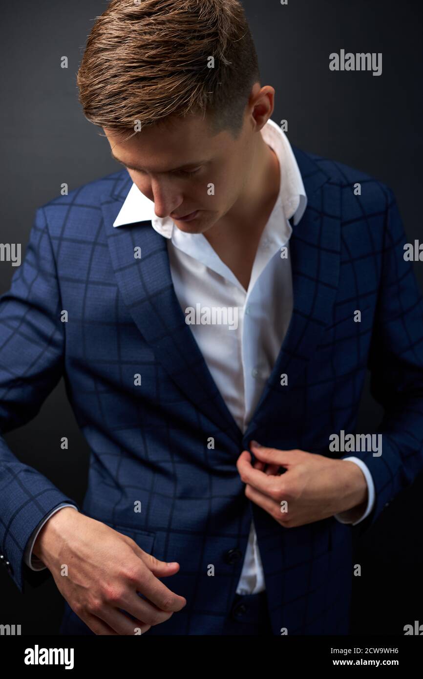 rich young male in classic formal suit or tux fixing button on jacket ...