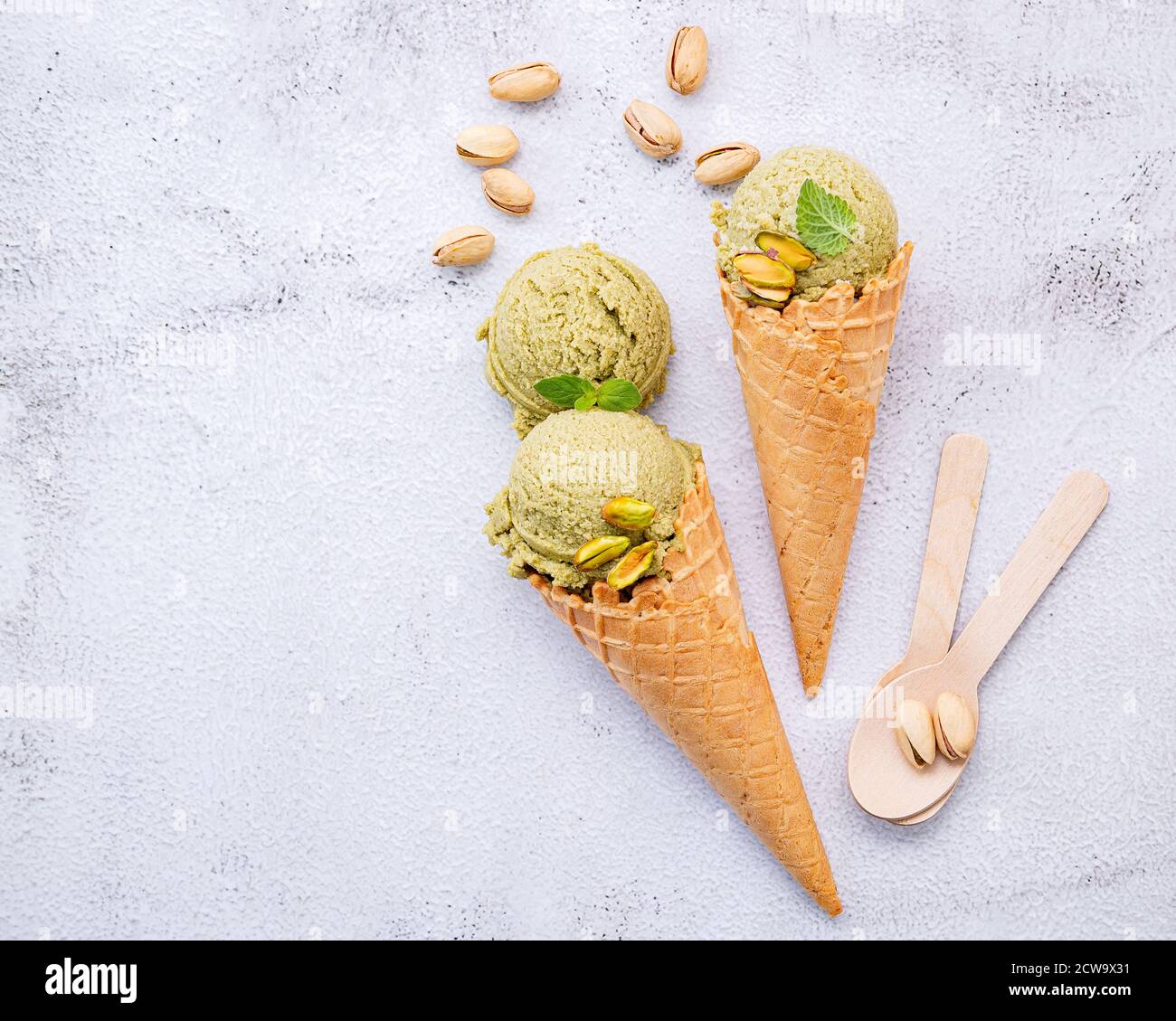 Pistachio ice cream in cones with pistachio nuts setup on white stone ...