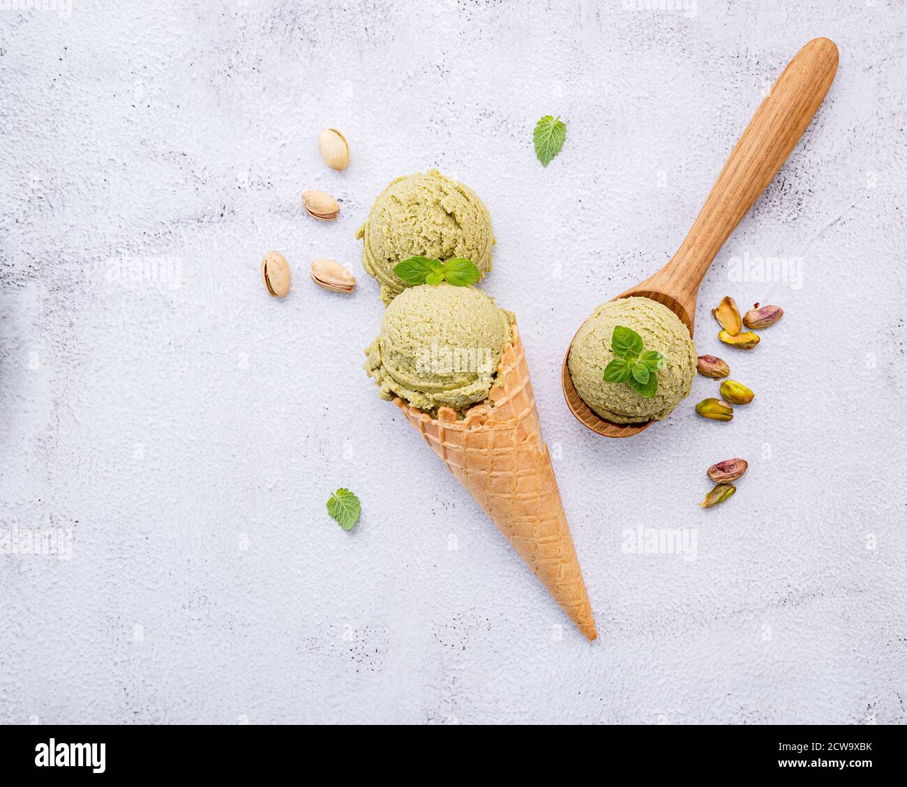 Pistachio ice cream in cones with pistachio nuts setup on white stone ...