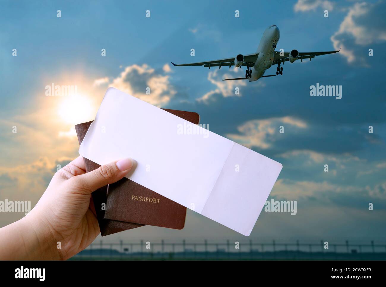 hand holding boarding pass and passport book with plane flying ...