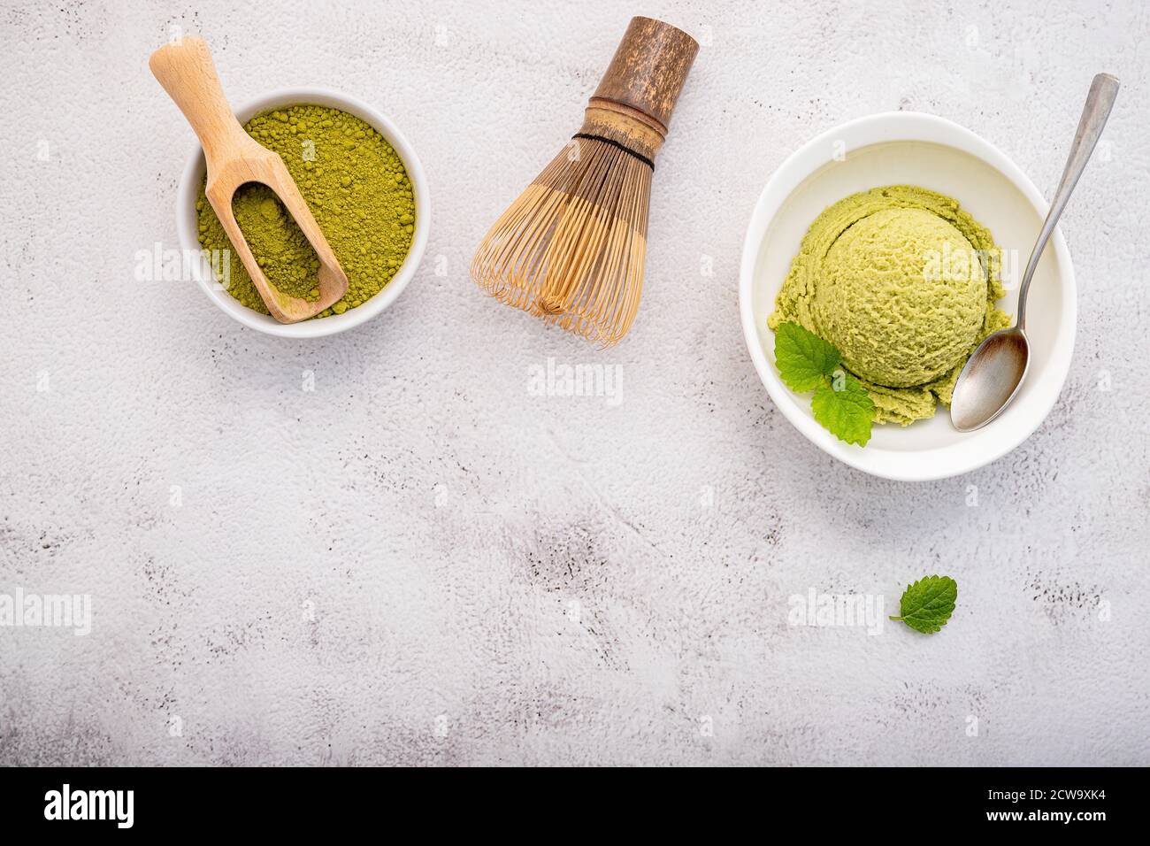 Matcha green tea ice cream with matcha whisk brush setup on white stone ...