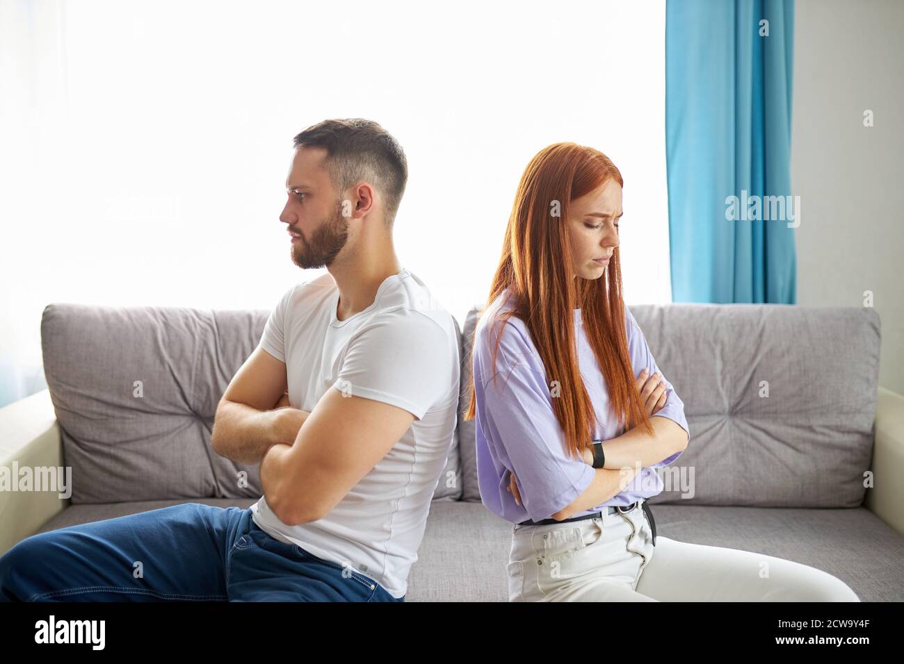 young caucasian couple offended on each other, sit turning away from ... young caucasian couple offended on each other, sit turning away from ...
