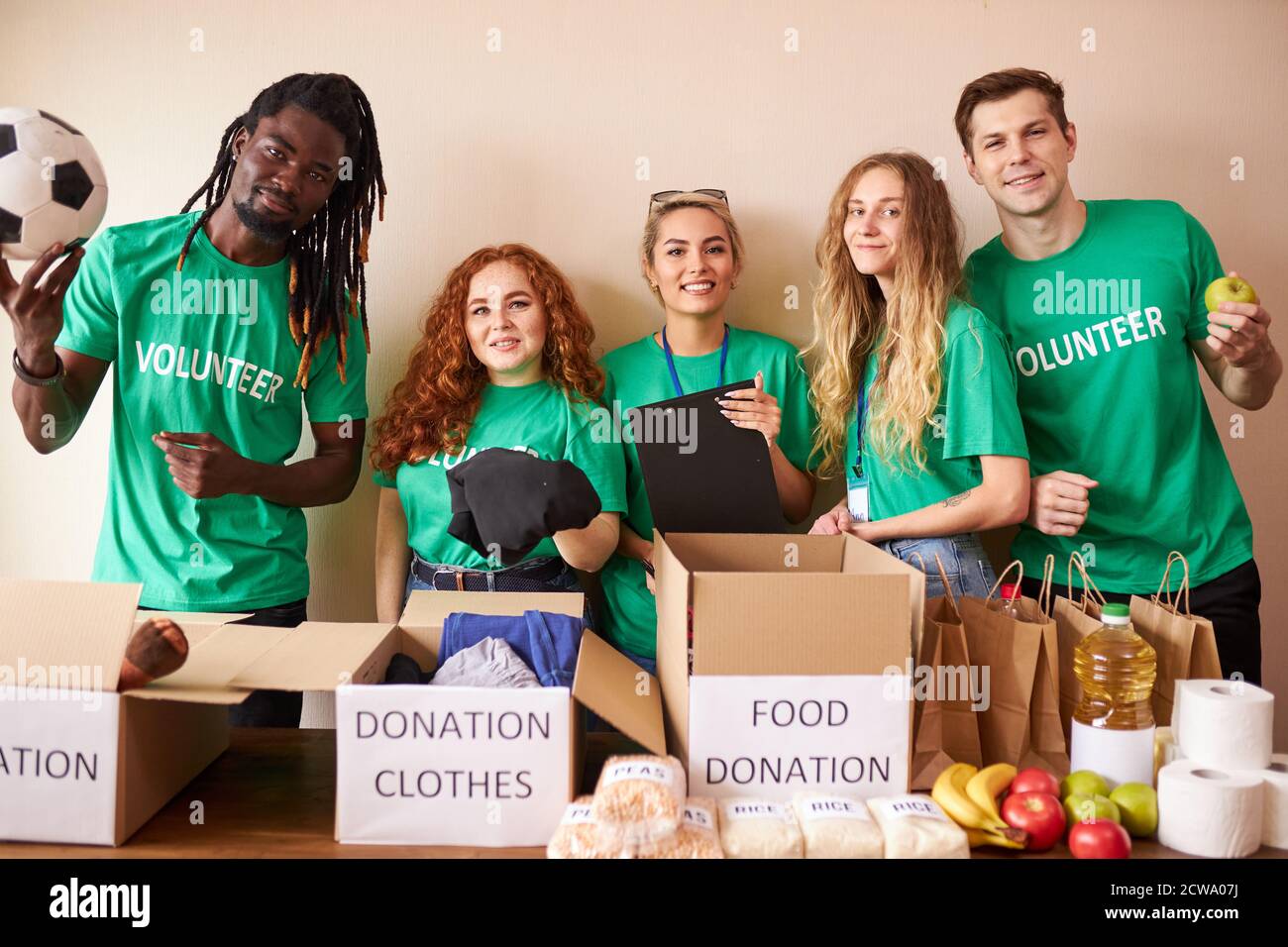 diverse volunteers packing, collecting humanitarian aid in donation box ...