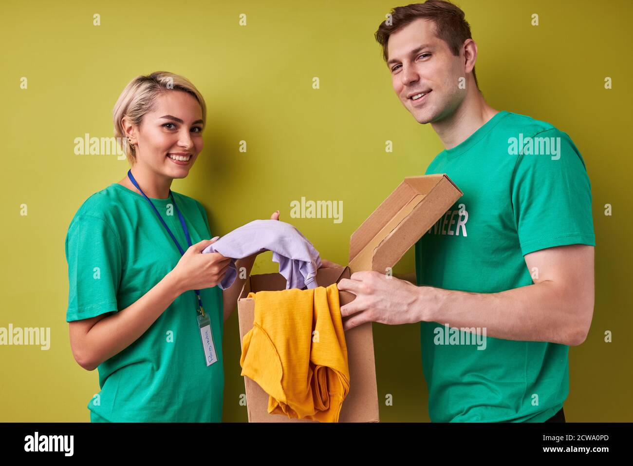happy young volunteers donating clothes and food for charity, indoors ...
