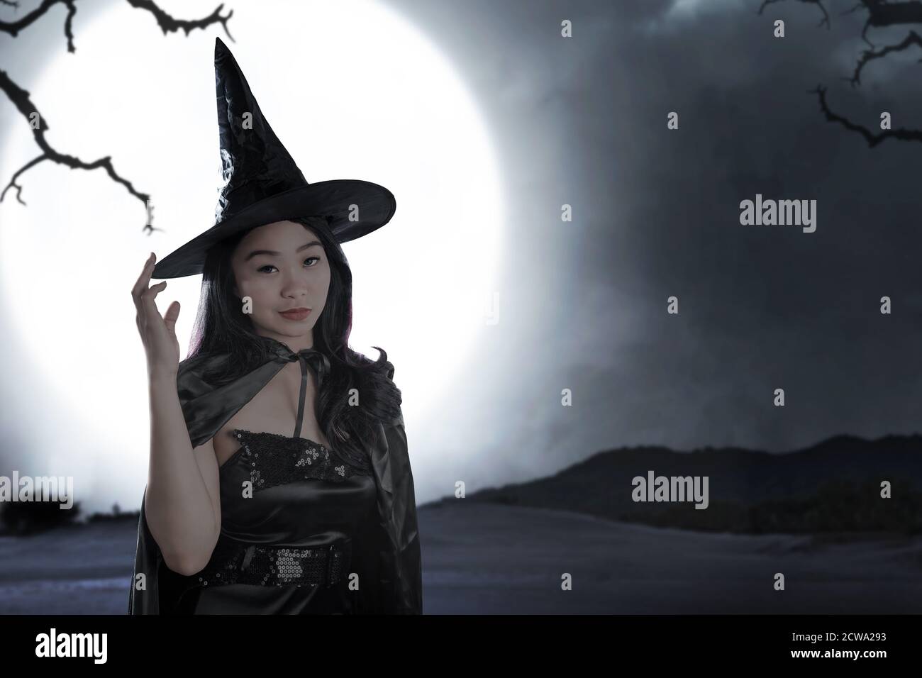 Asian witch woman with a hat standing with the night scene background ...