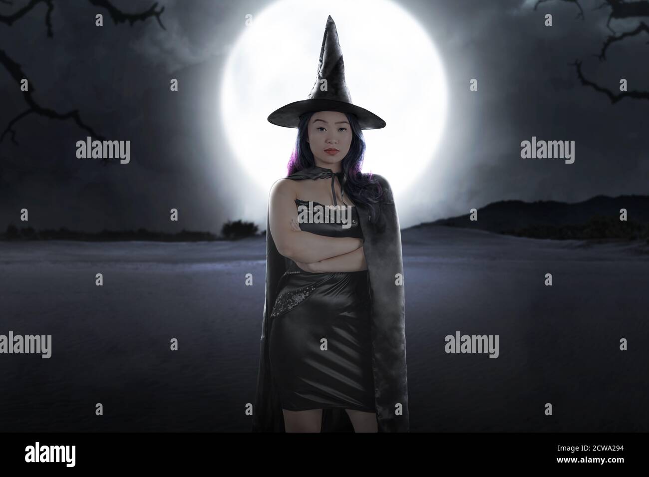 Asian witch woman with a hat standing with the night scene background ...