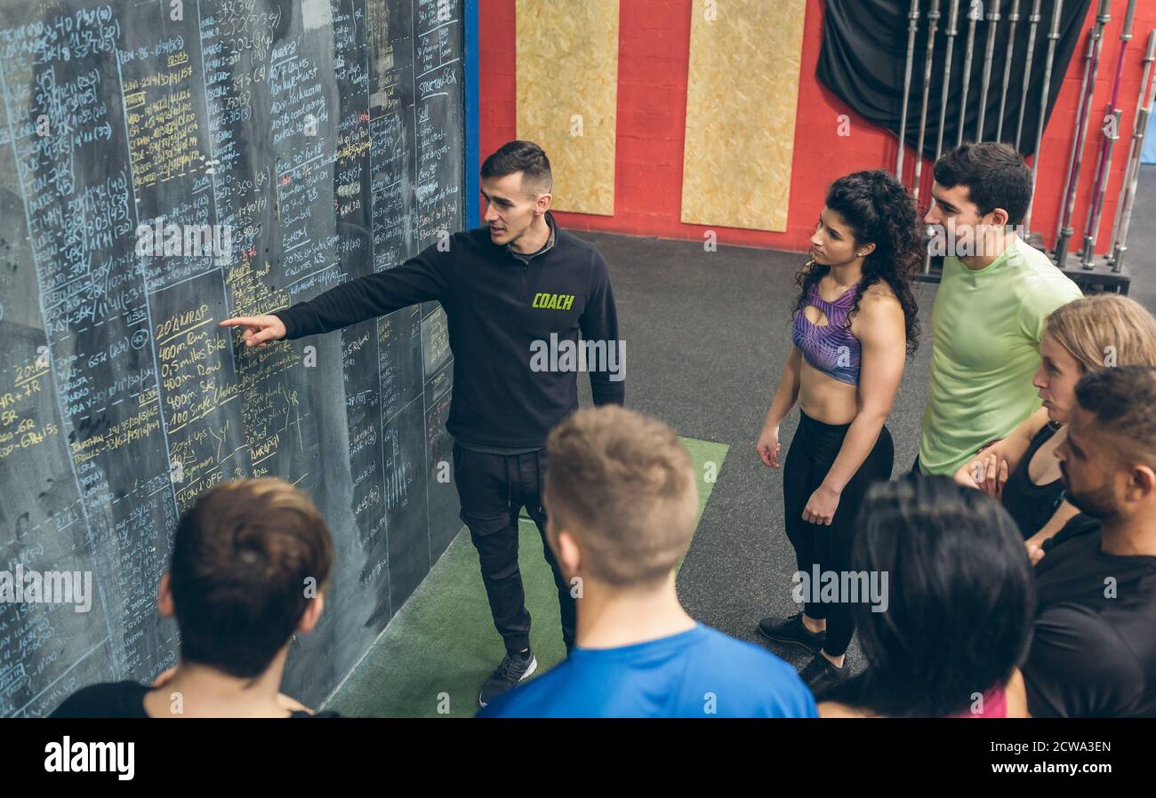 Coach explaining to athletes in the gym Stock Photo - Alamy