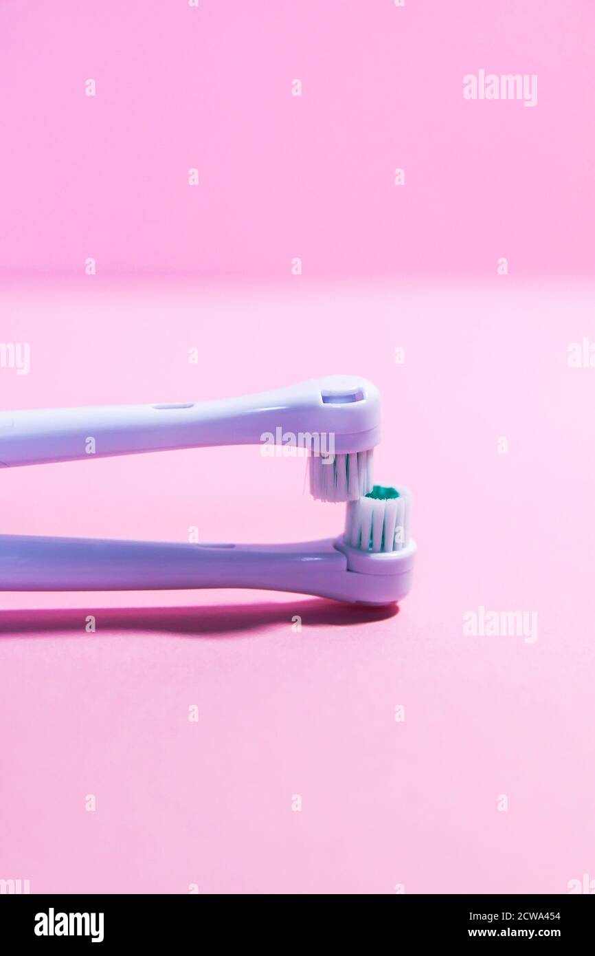 Two electrical toothbrushes on a soft light pink background Stock Photo ...