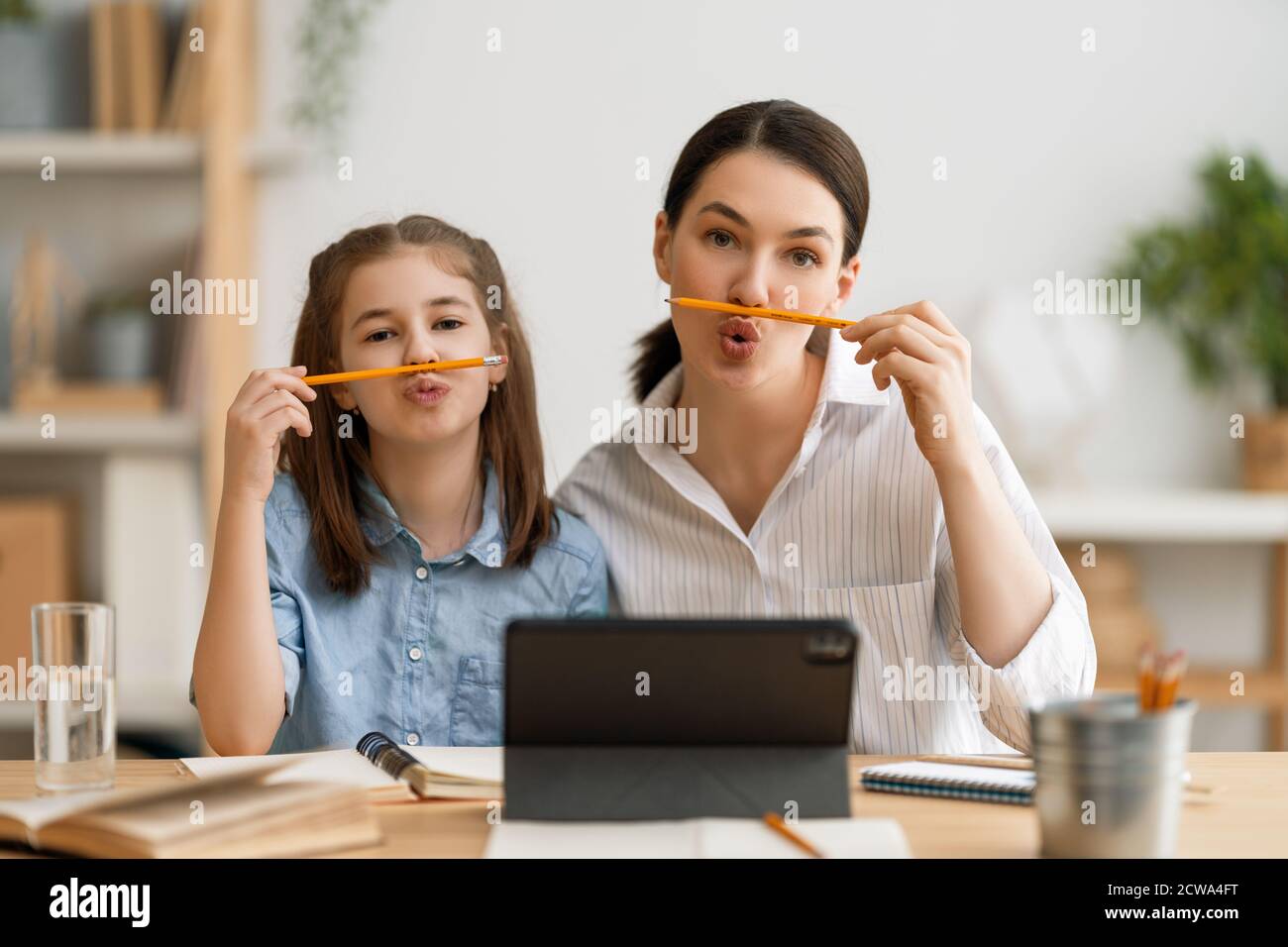 Back to school. Happy child and adult are sitting at desk. Girl doing ...