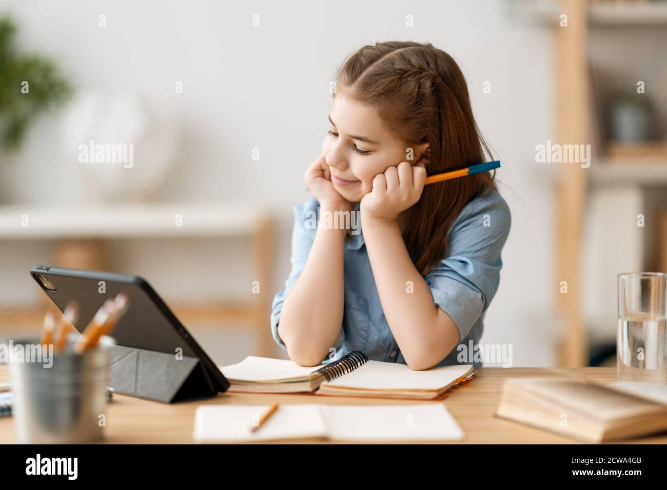 Back to school. Happy child is sitting at desk. Girl doing homework or ...