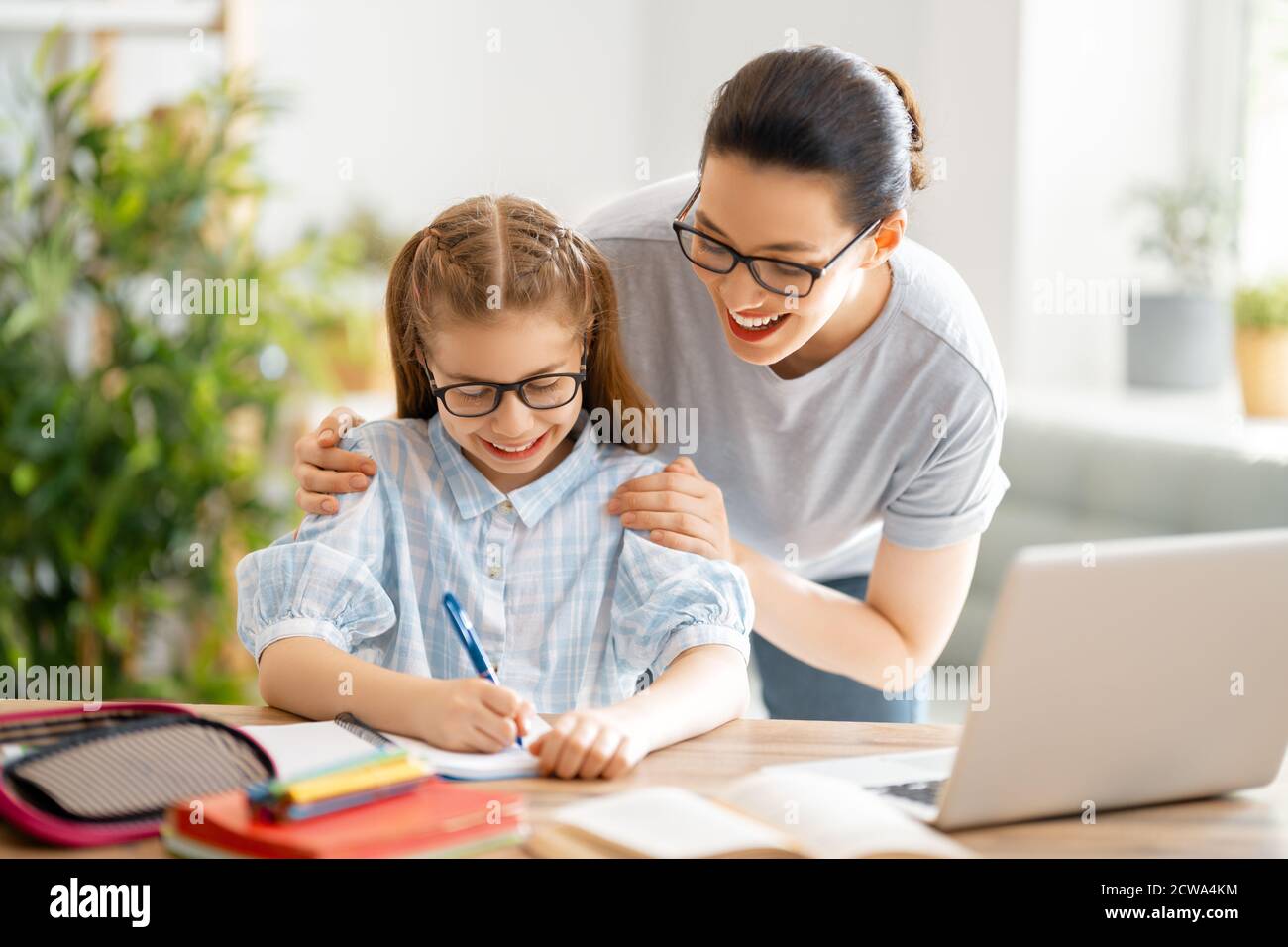 Back to school. Happy child and adult are sitting at desk. Girl doing ...