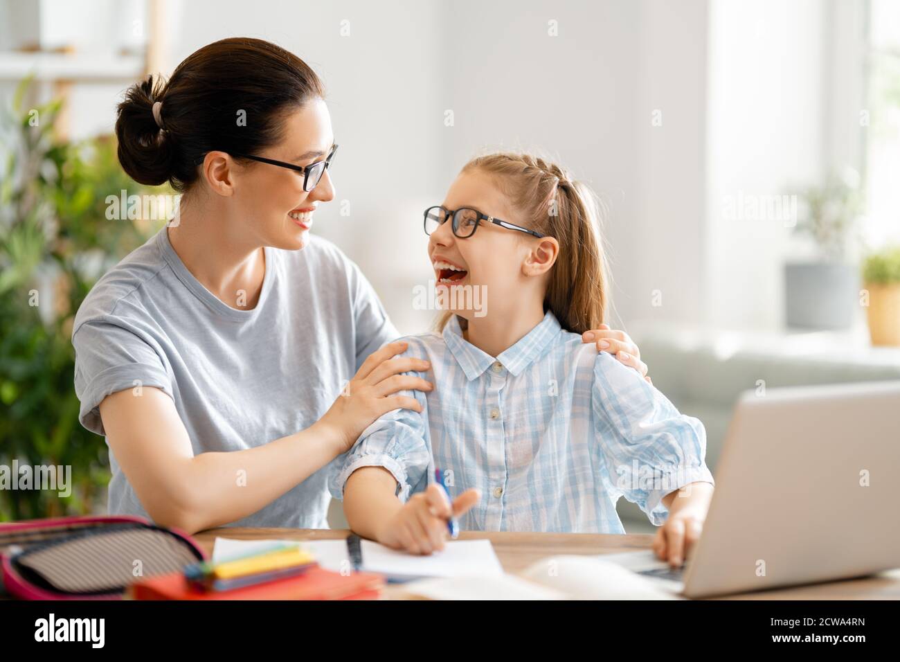 Back to school. Happy child and adult are sitting at desk. Girl doing ...
