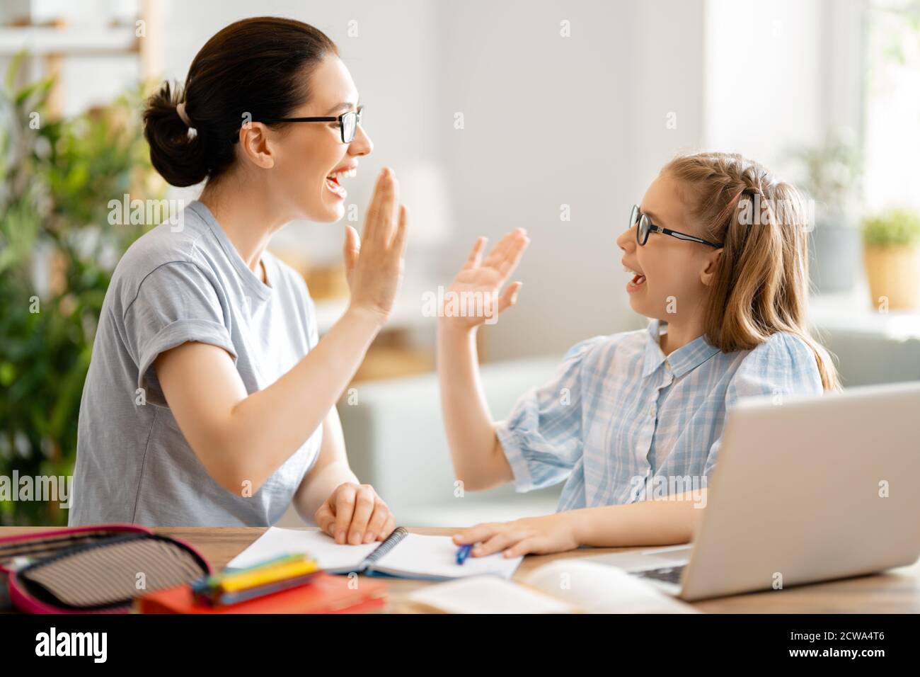 Back to school. Happy child and adult are sitting at desk. Girl doing ...