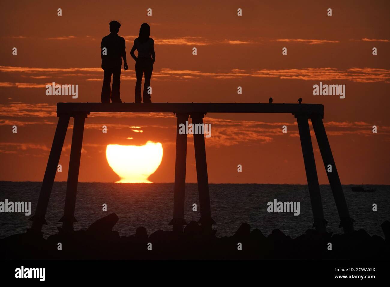 The sun rises behind Sean Henry's The Couple Statue at Newbiggin-by-the ...