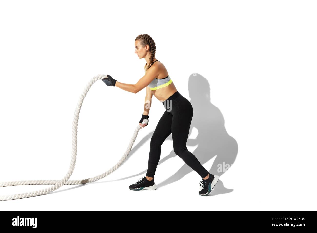 Ropes. Beautiful young female athlete practicing on white studio ...