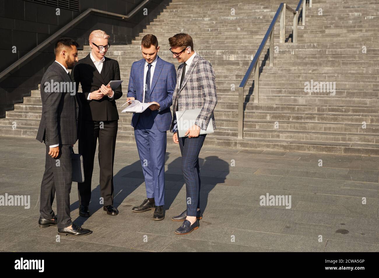 Group of business people standing together outdoors and examining ...