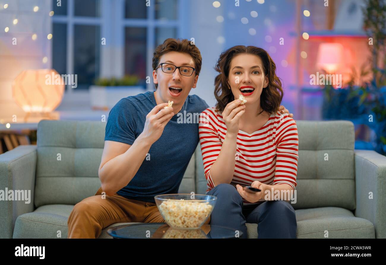 Happy family watching projector, TV, movies with popcorn in the evening ...