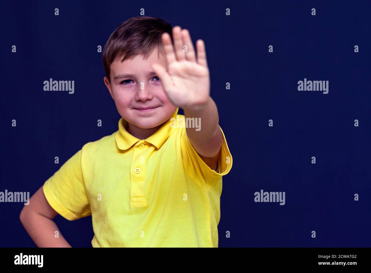 Little 9s boy putting his hand out making stop sign gesture.Blue studio ...