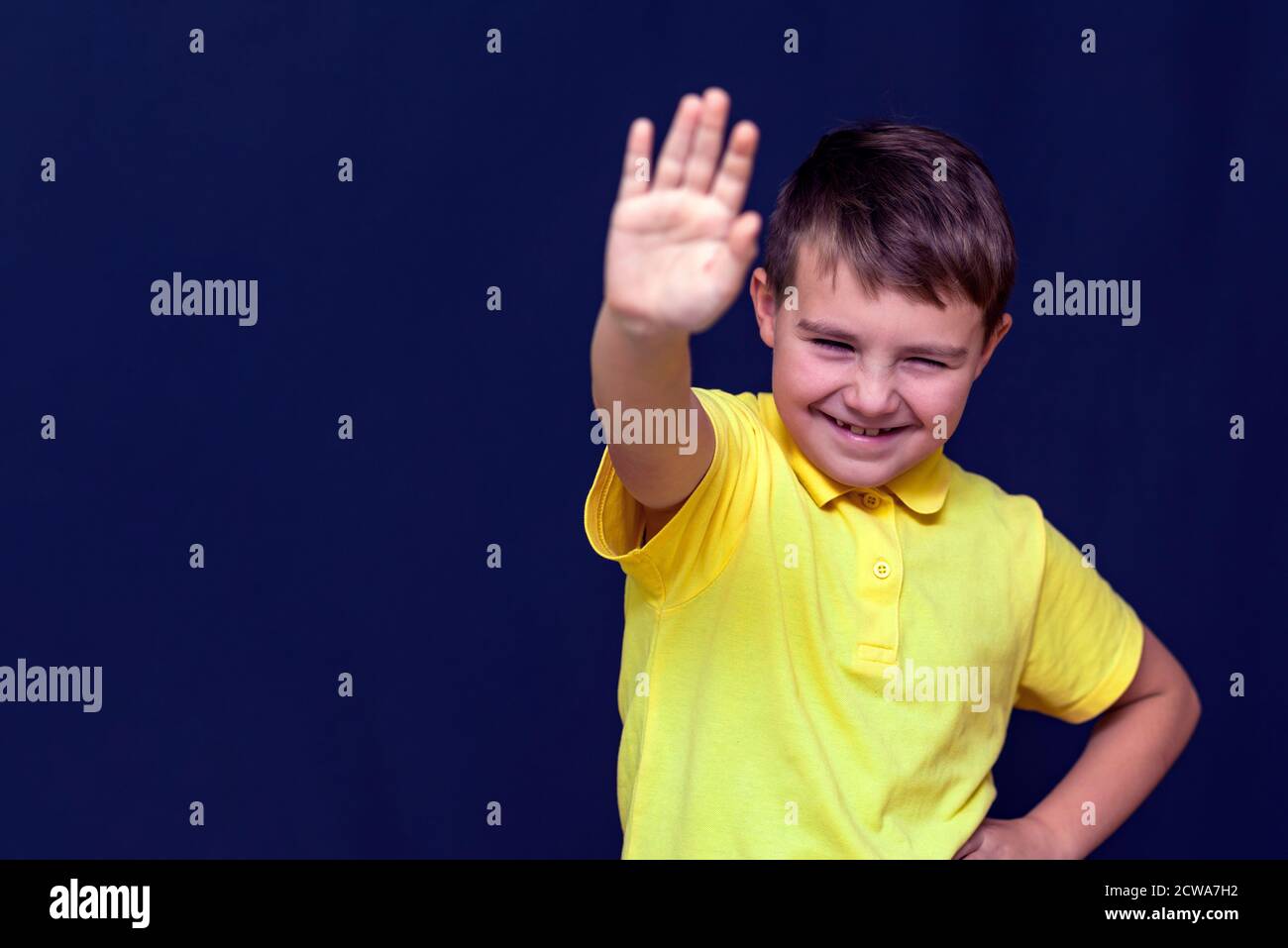 Little 9s boy putting his hand out making stop sign gesture.Blue studio ...