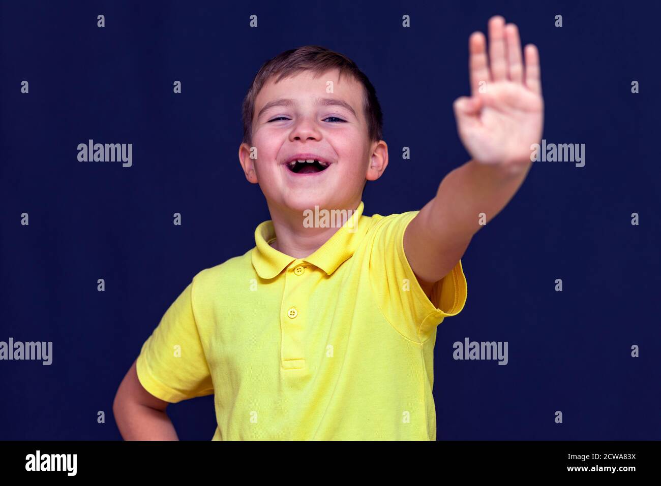 Little 9s boy putting his hand out making stop sign gesture.Blue studio ...