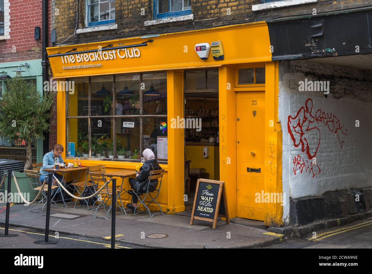 Two young women seated at pavement tables outside the Breakfast Club ...