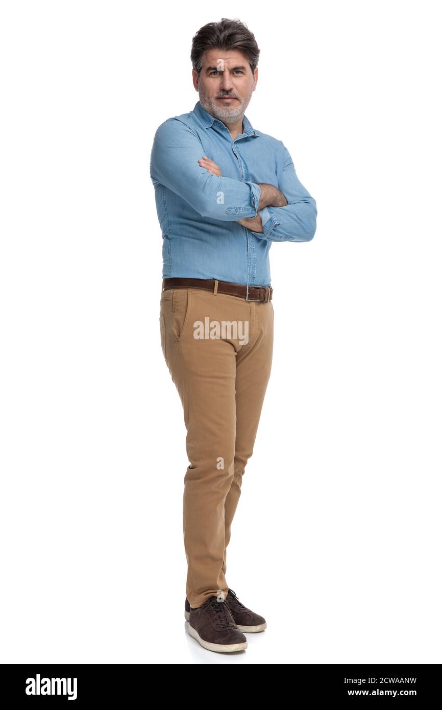Tough casual man holding his arms folded while standing on white studio ...