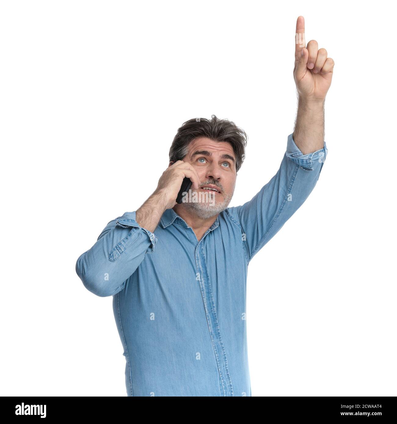 Eager casual man talking on his phone and pointing up while standing on ...