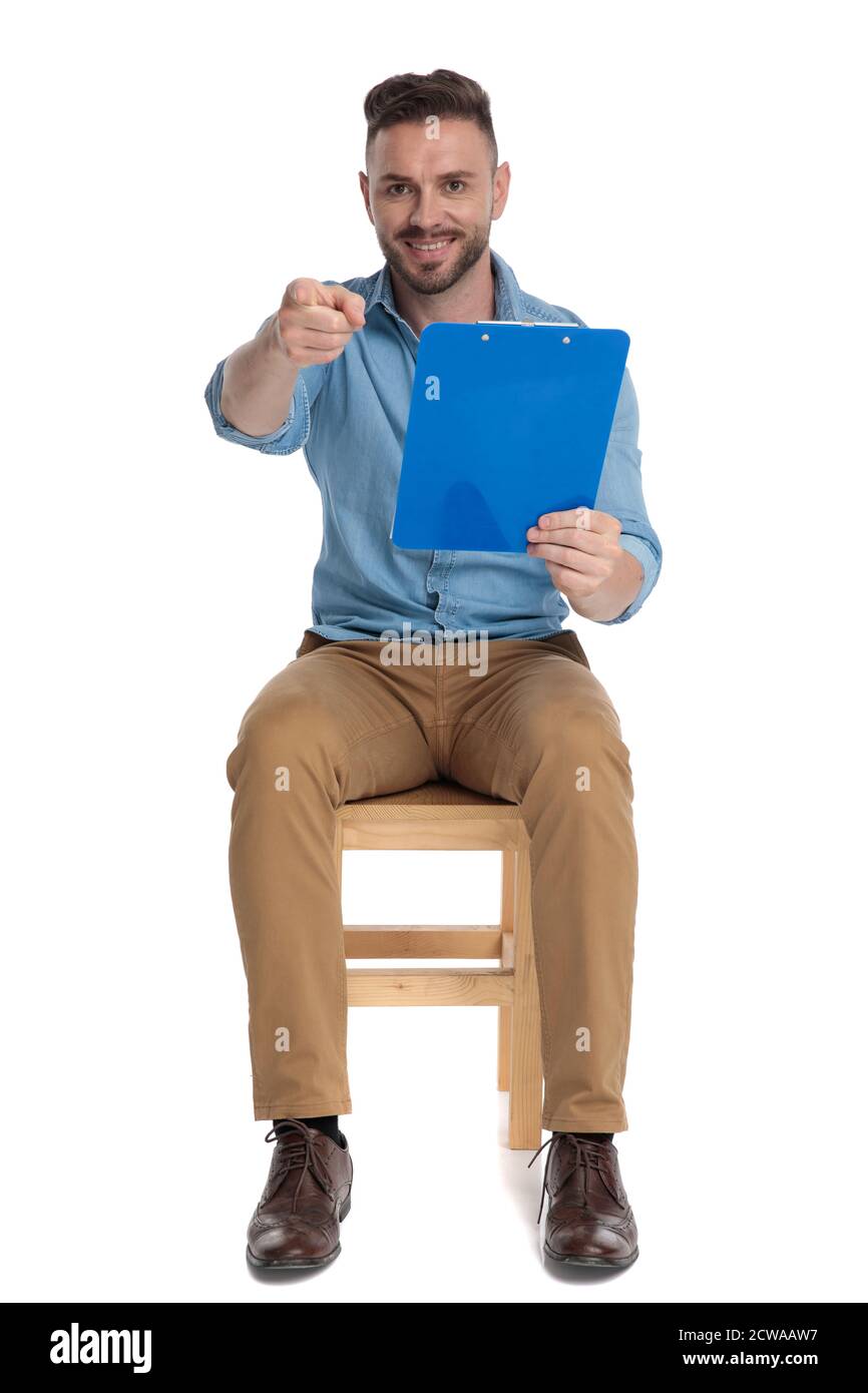 young casual guy holding clipboard and pointing finger, sitting ...