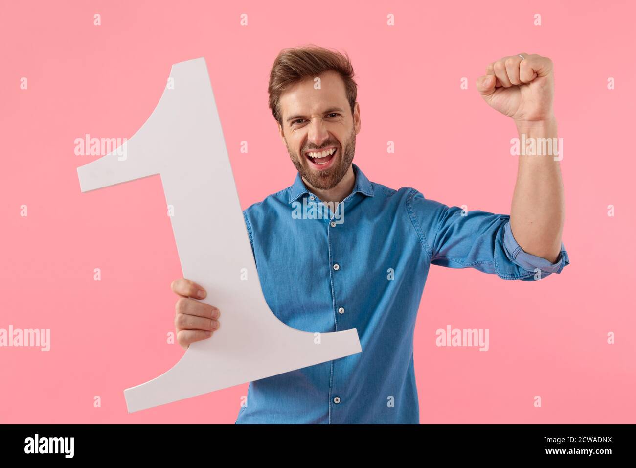 happy young guy holding number one sign and celebrating victory ...