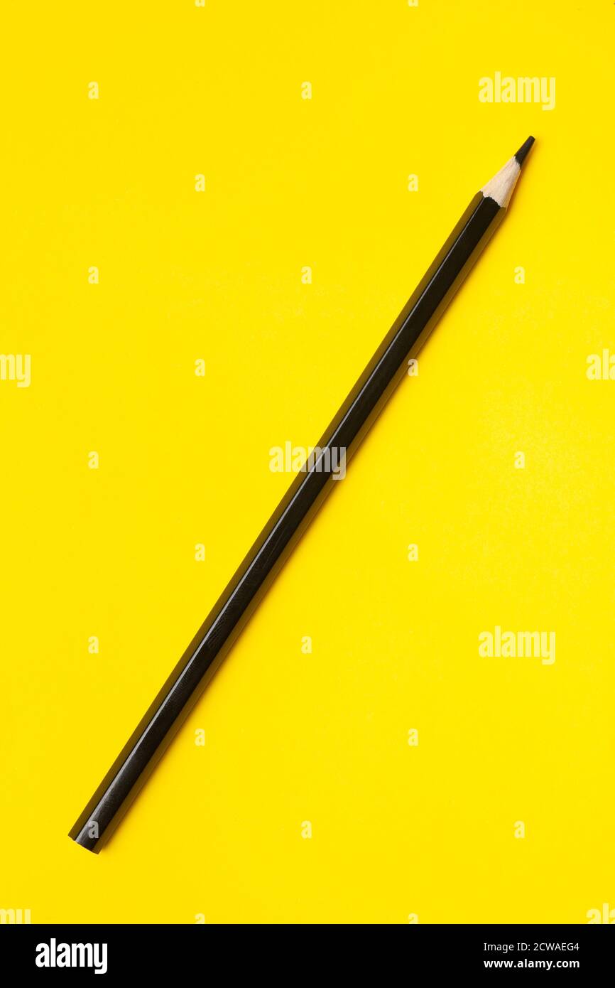diagonal black sharp wooden pencil on a bright yellow background ...
