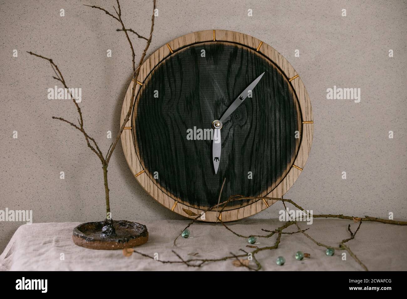 Wall black burned round wooden clocks on table with grey linen ...